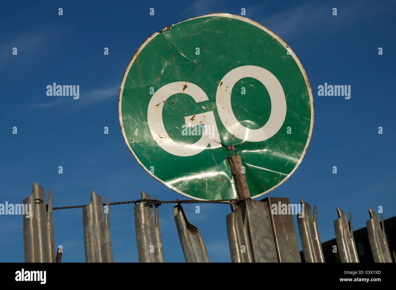 Metaphor. Positive concept. A circular GO sign, battered and worn, with ...