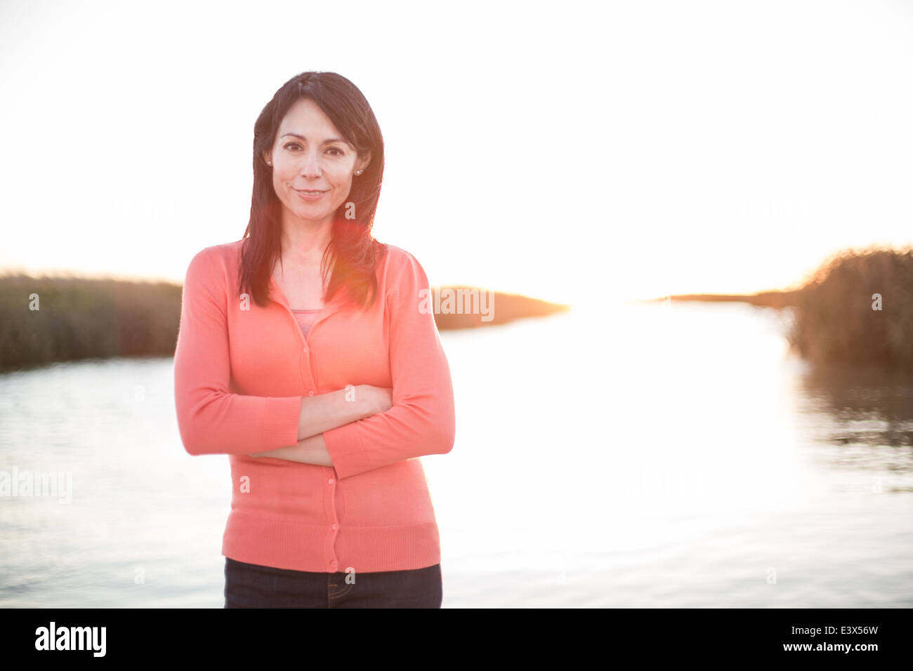 Woman with hands folded over chest smiles confidently at camera in ...