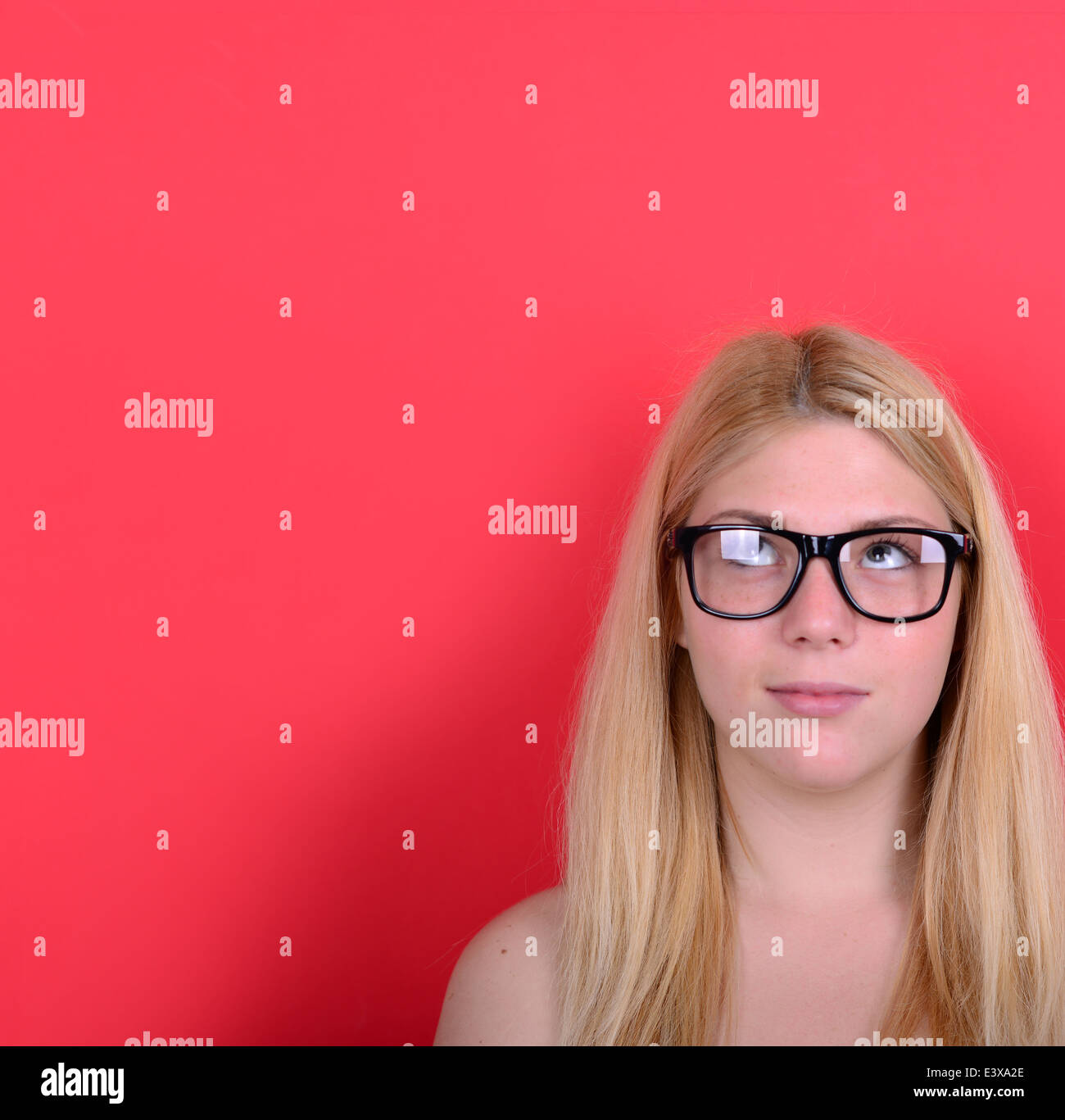 Portrait of beautiful girl thinking and looking up against red ...