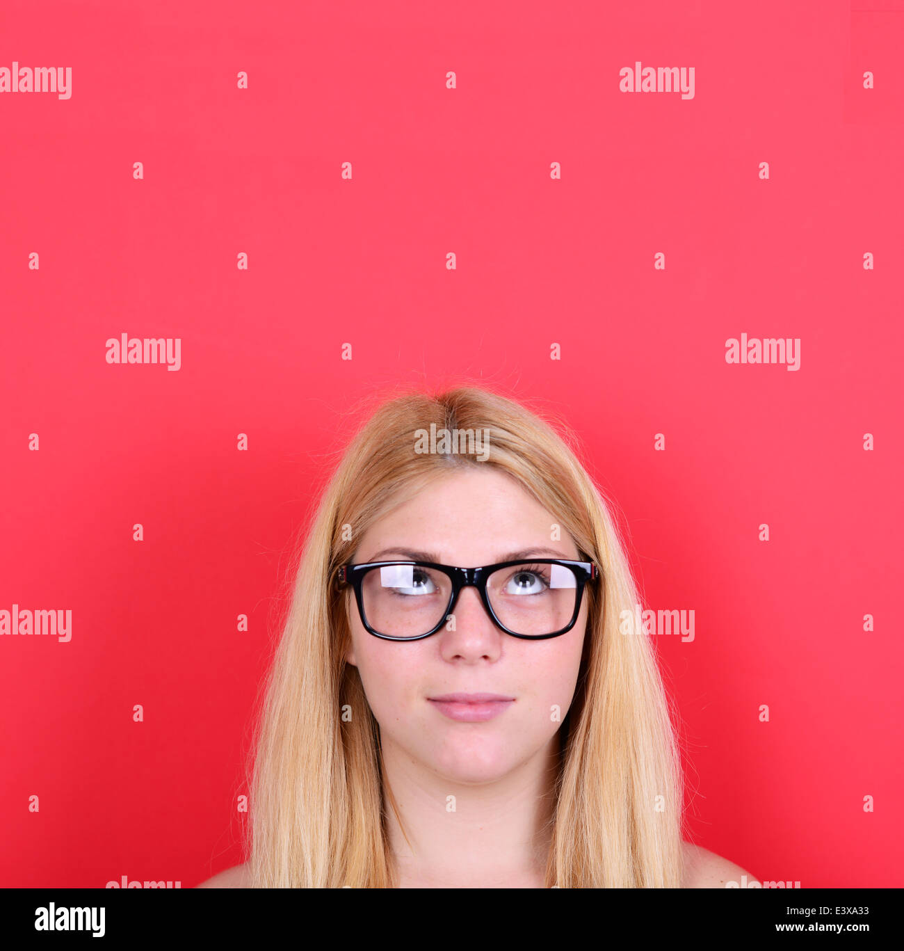 Portrait of beautiful girl thinking and looking up against red ...