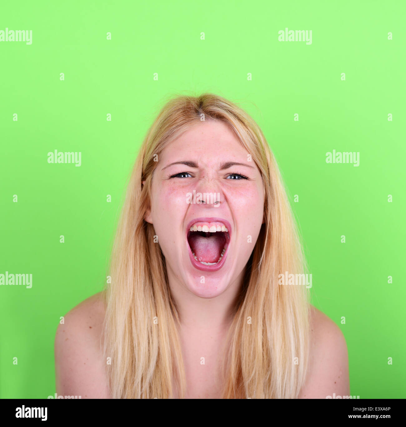 Portrait of desperate blond young woman screaming against green ...