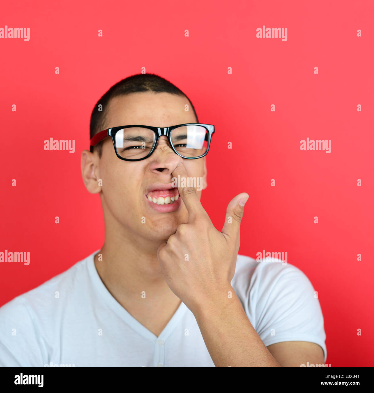 Portrait of a funny guy with finger in his nose against red background ...