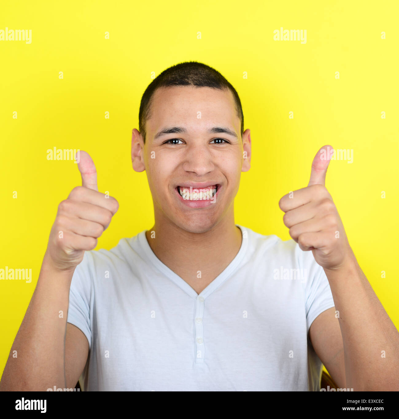 Portrait of with funny expression holding thumbs up against yellow ...