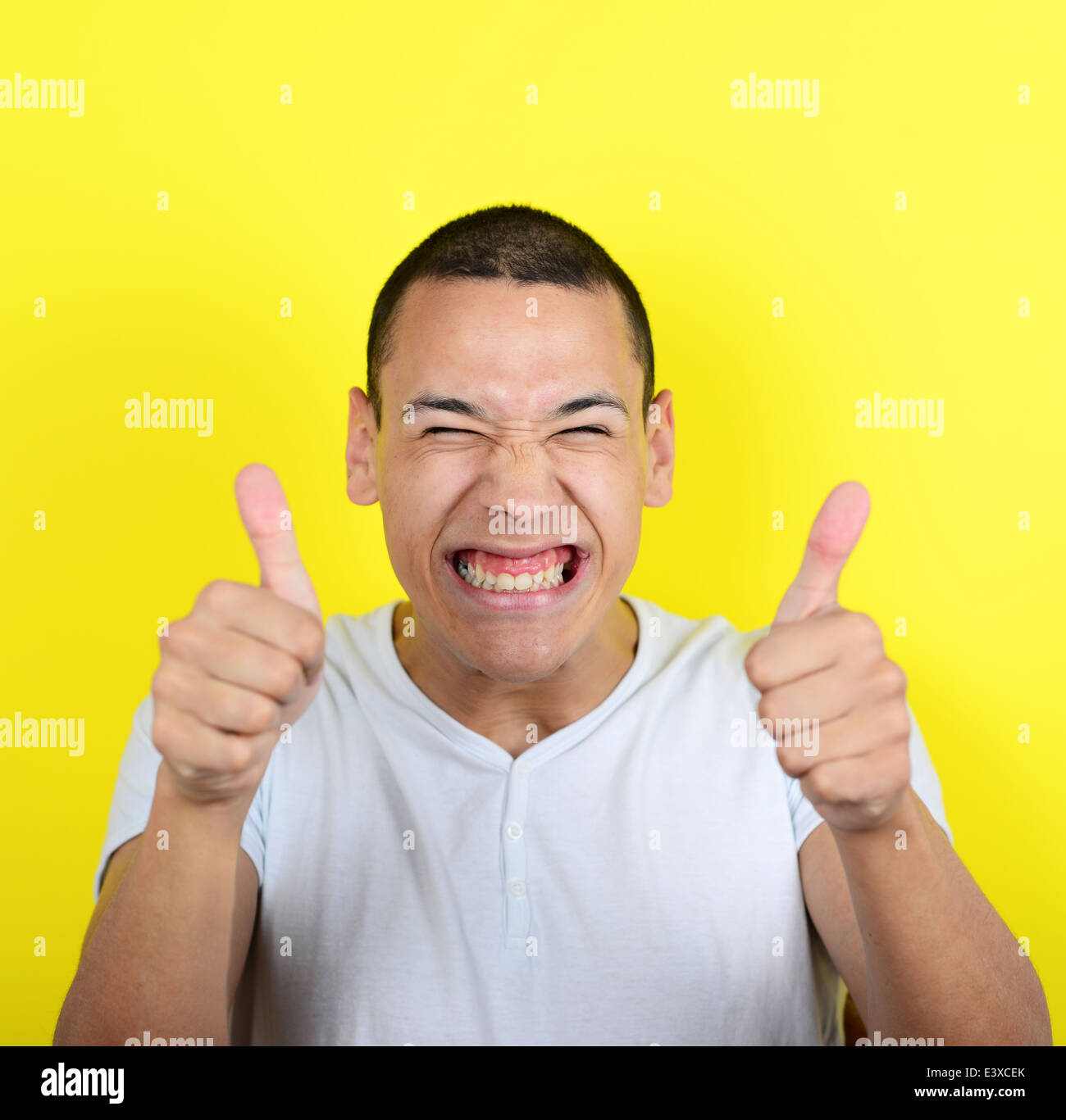 Portrait of with funny expression holding thumbs up against yellow ...