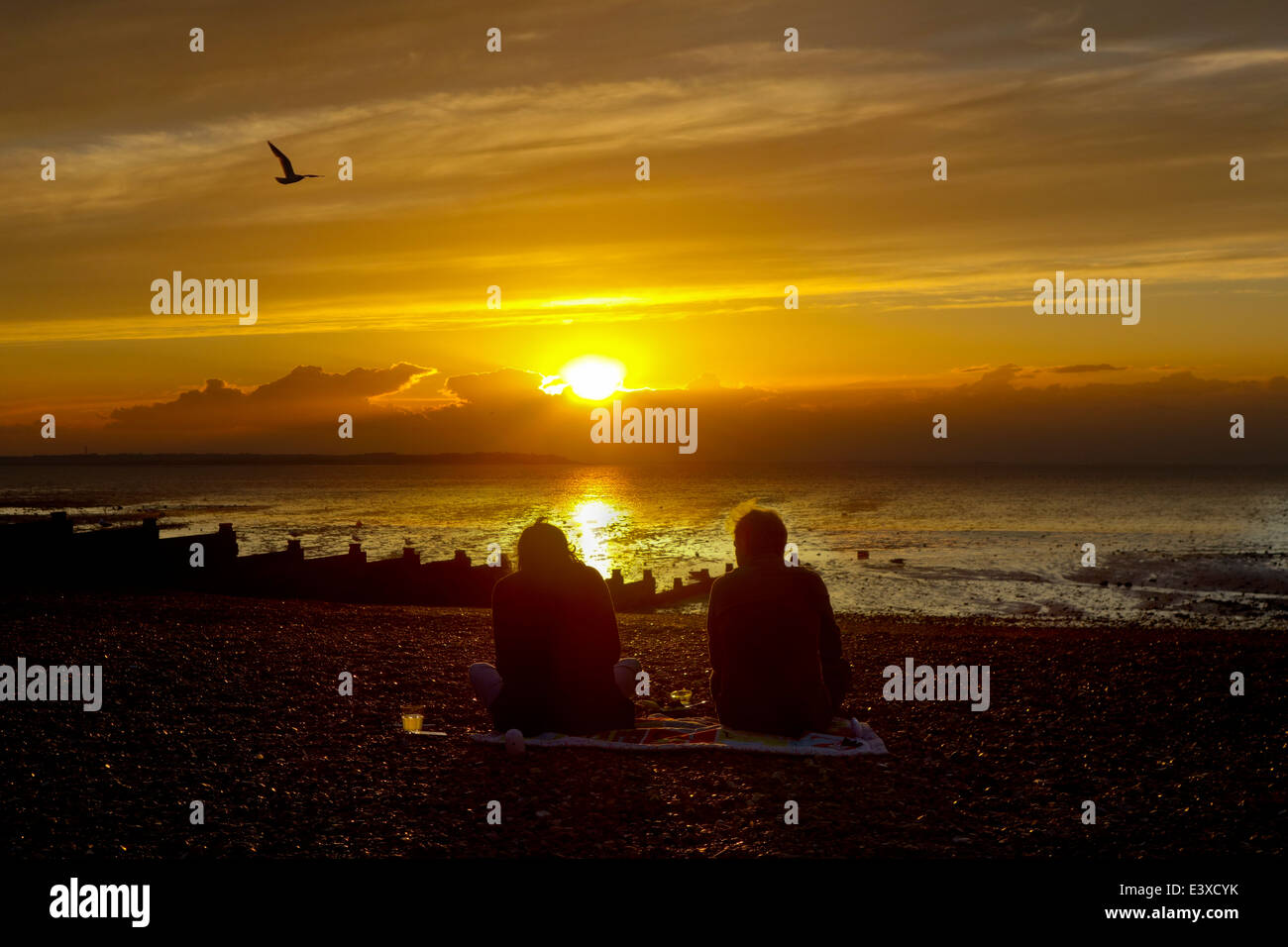 couple sit and watch sunset Whitstable beach Stock Photo - Alamy