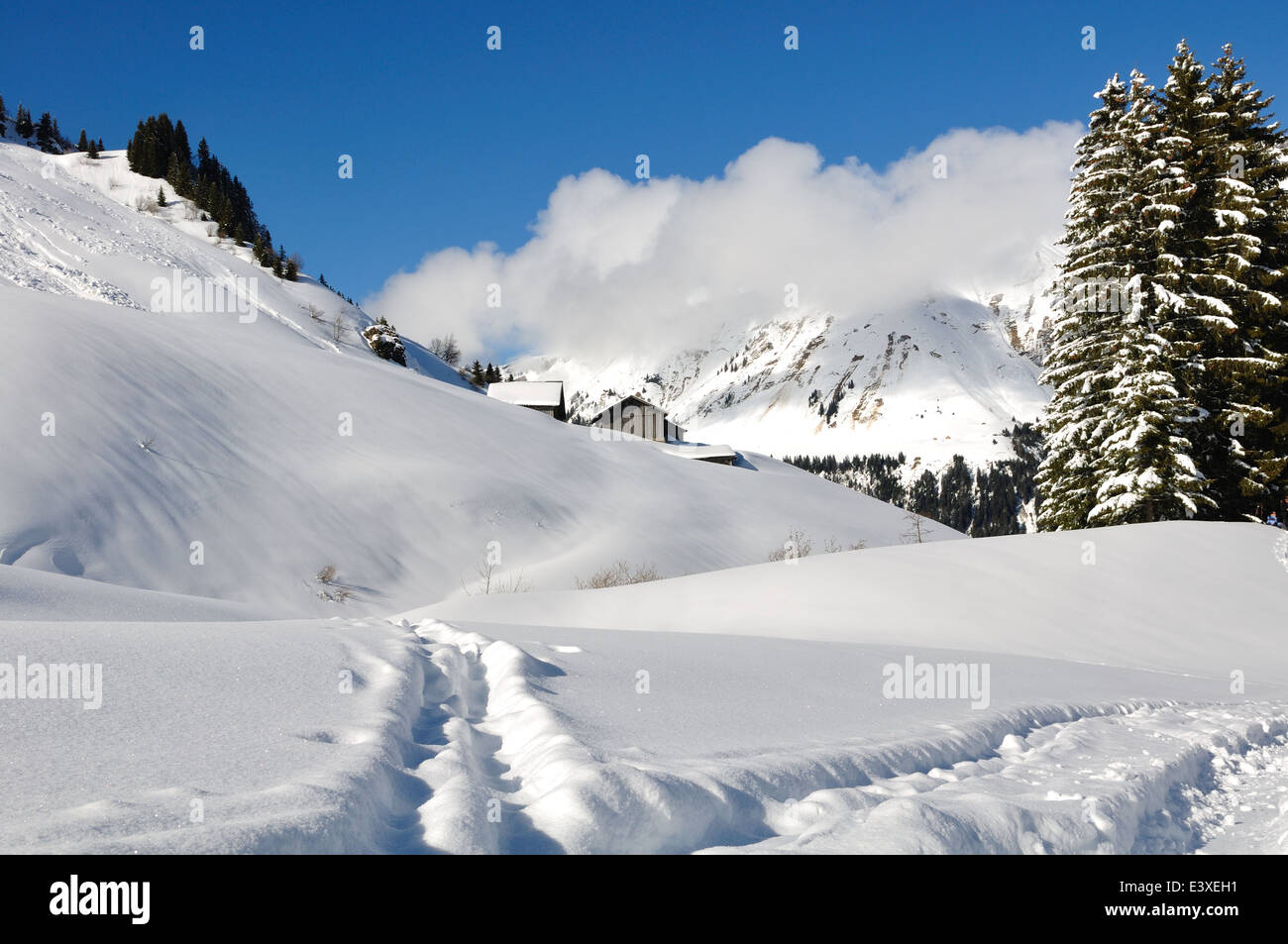 path in the snow leading through the mountains and a small village ...