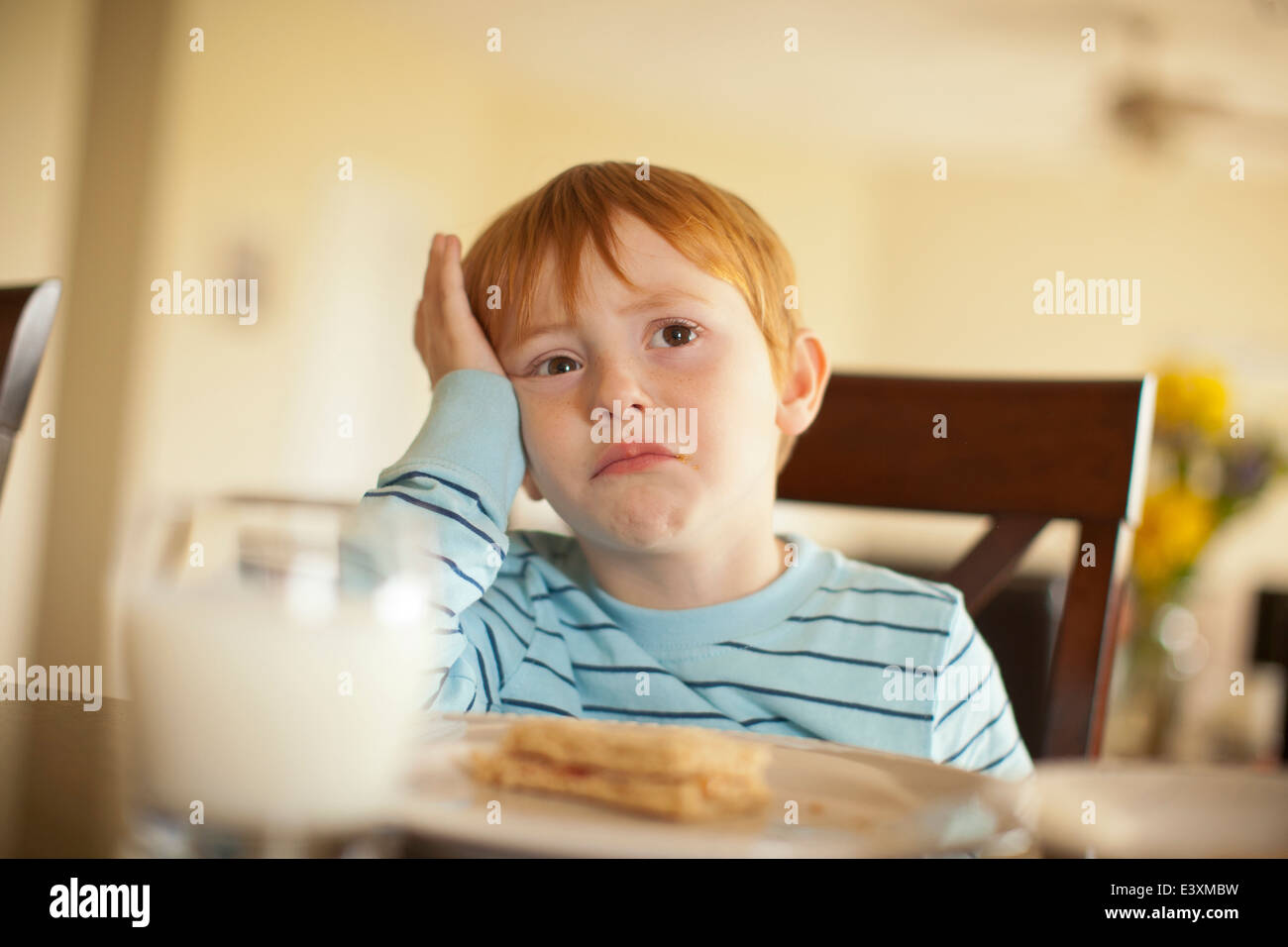 Caucasian boy pouting at dinner table Stock Photo - Alamy