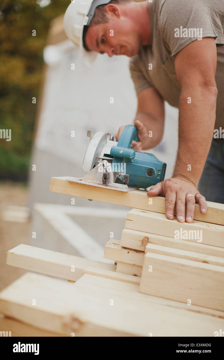 Caucasian construction worker sawing wood planks Stock Photo - Alamy