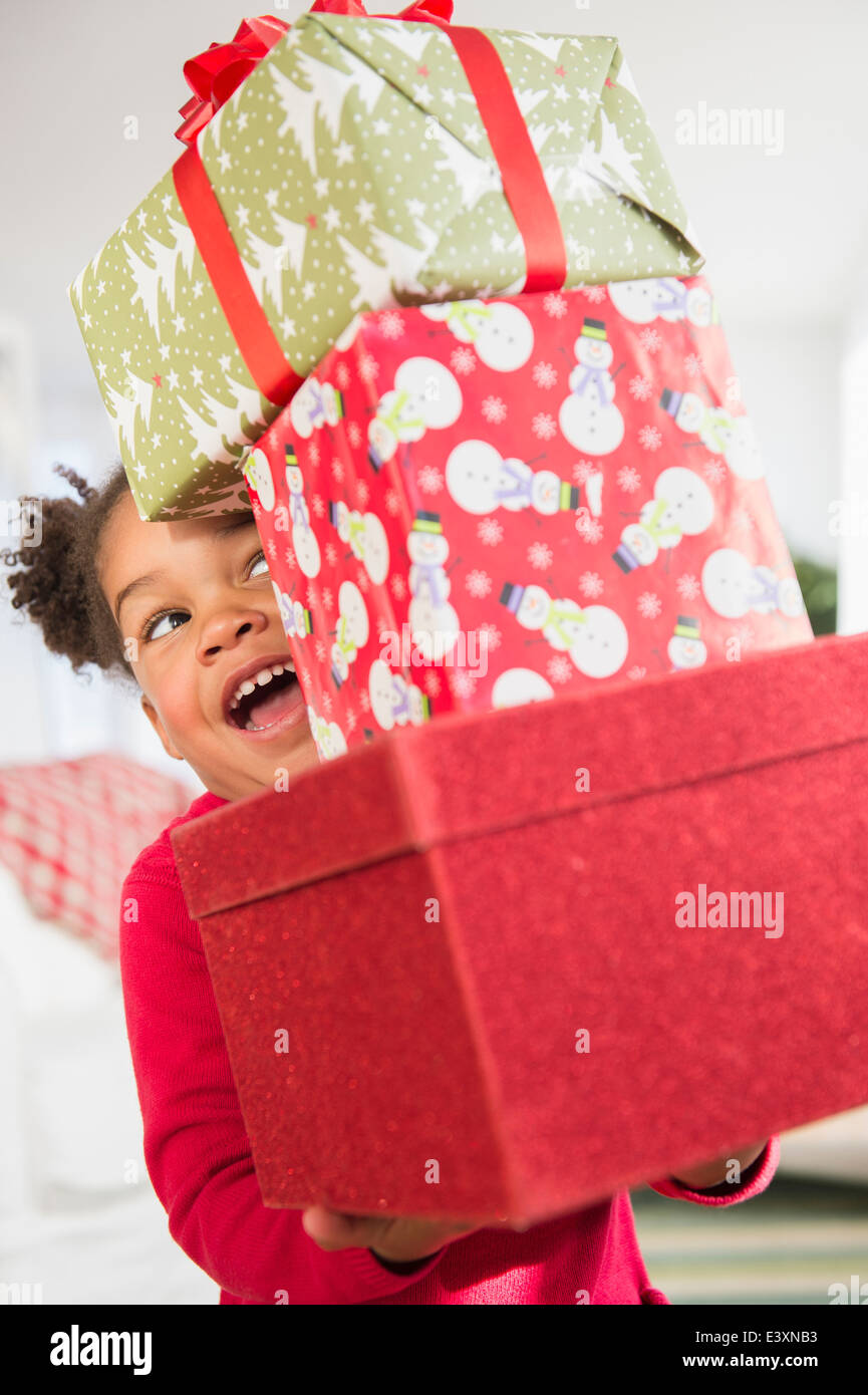 Black girl carrying stack of Christmas presents Stock Photo - Alamy