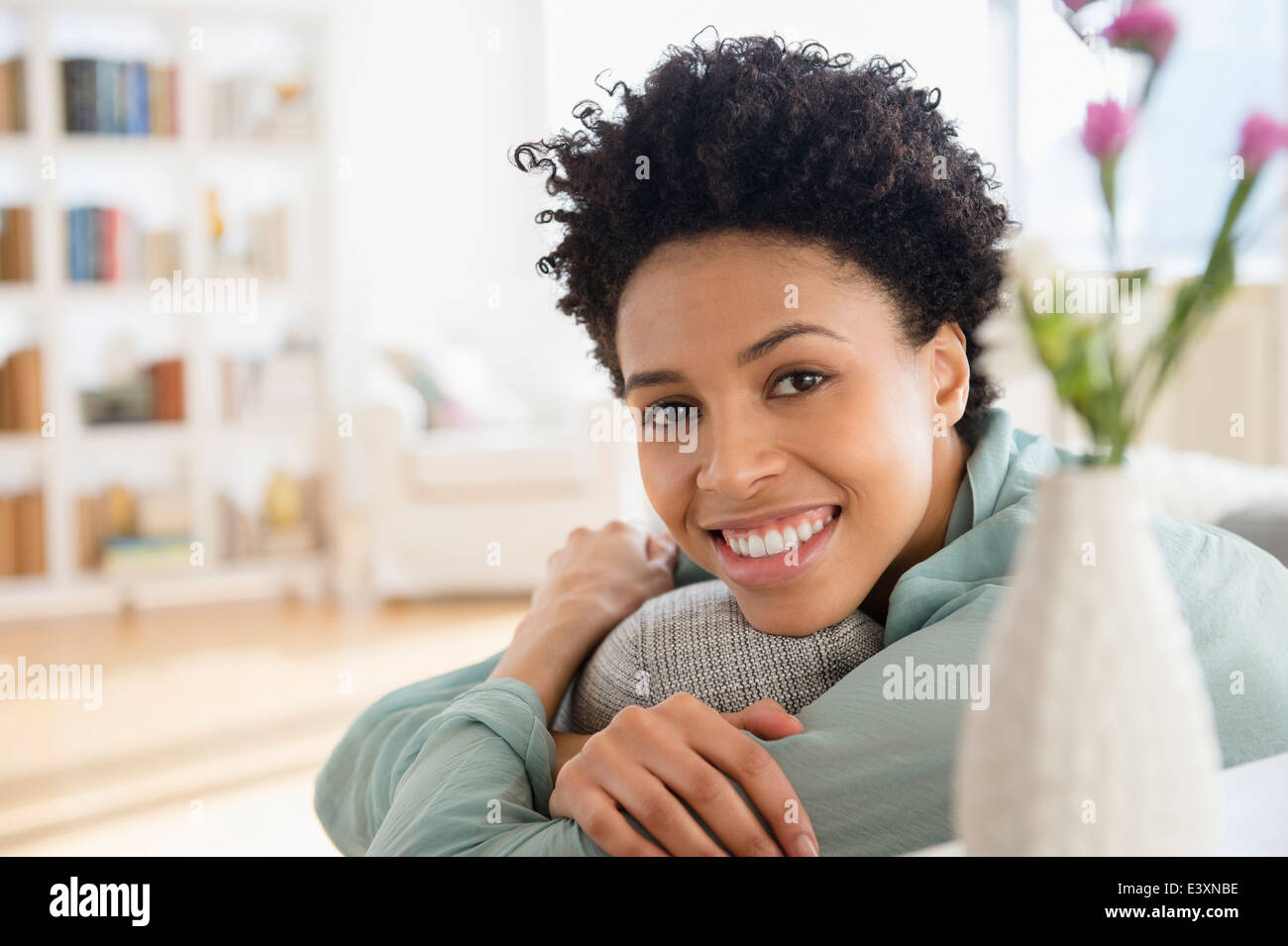 Black woman smiling on sofa Stock Photo - Alamy