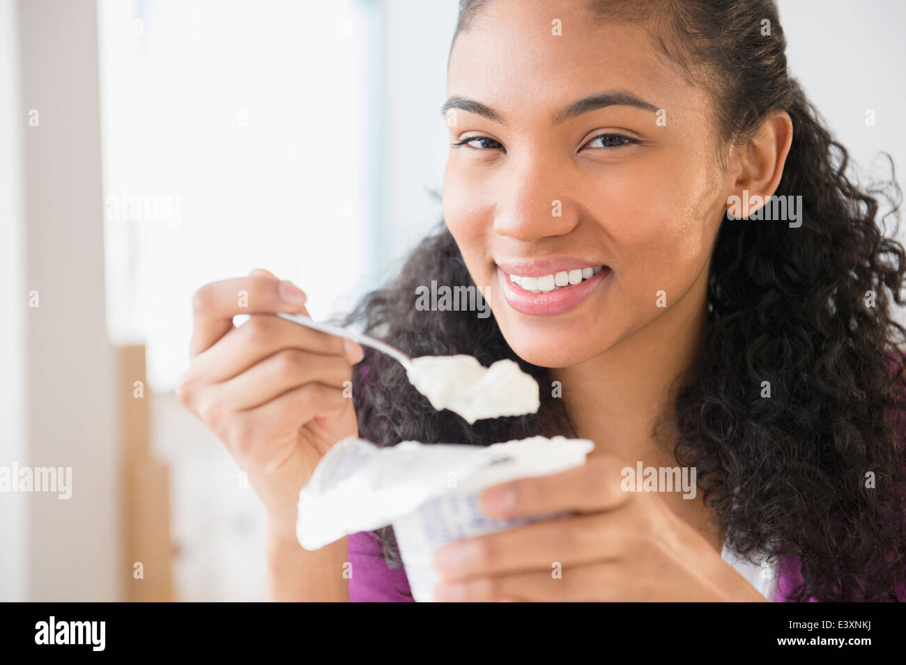 Mixed race woman eating yogurt Stock Photo - Alamy