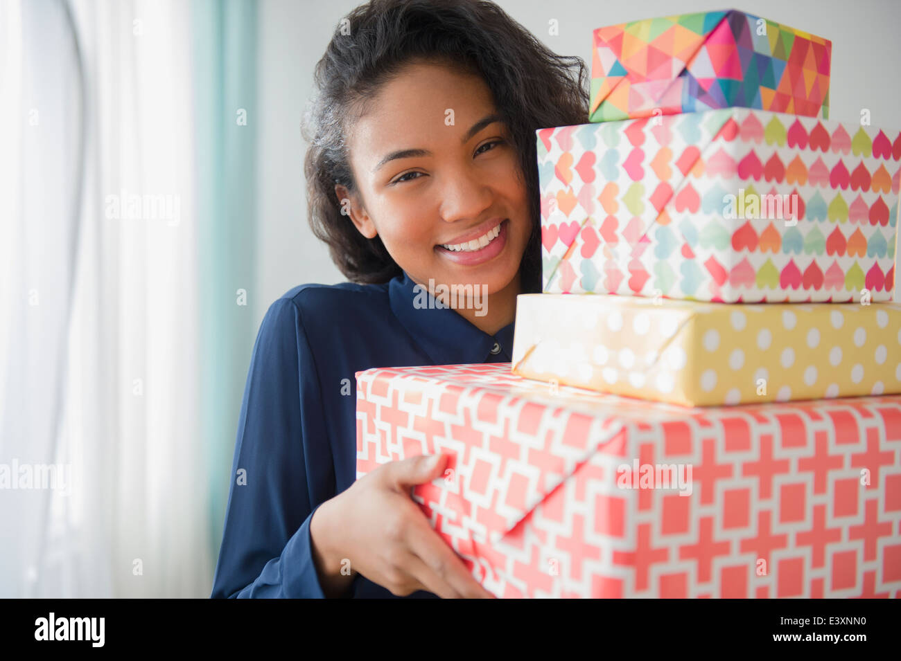 Mixed race woman carrying stack of gifts Stock Photo - Alamy