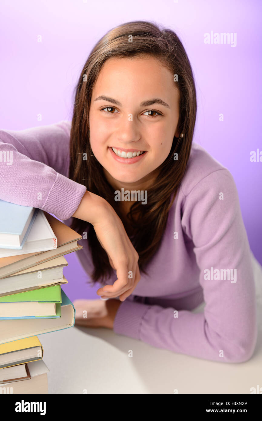 Smiling student girl with pile of books on purple background Stock ...