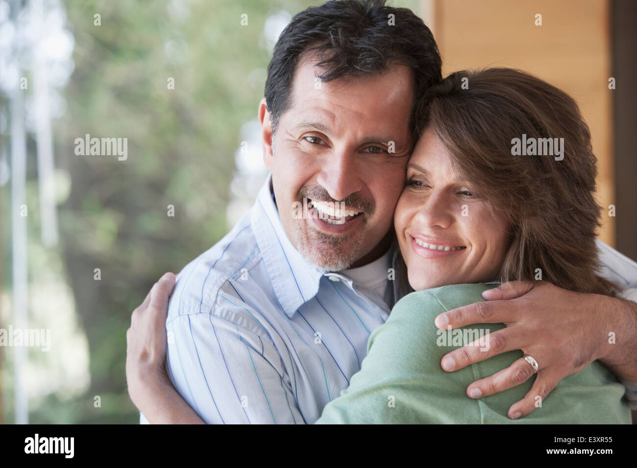 Hispanic couple hugging indoors Stock Photo - Alamy