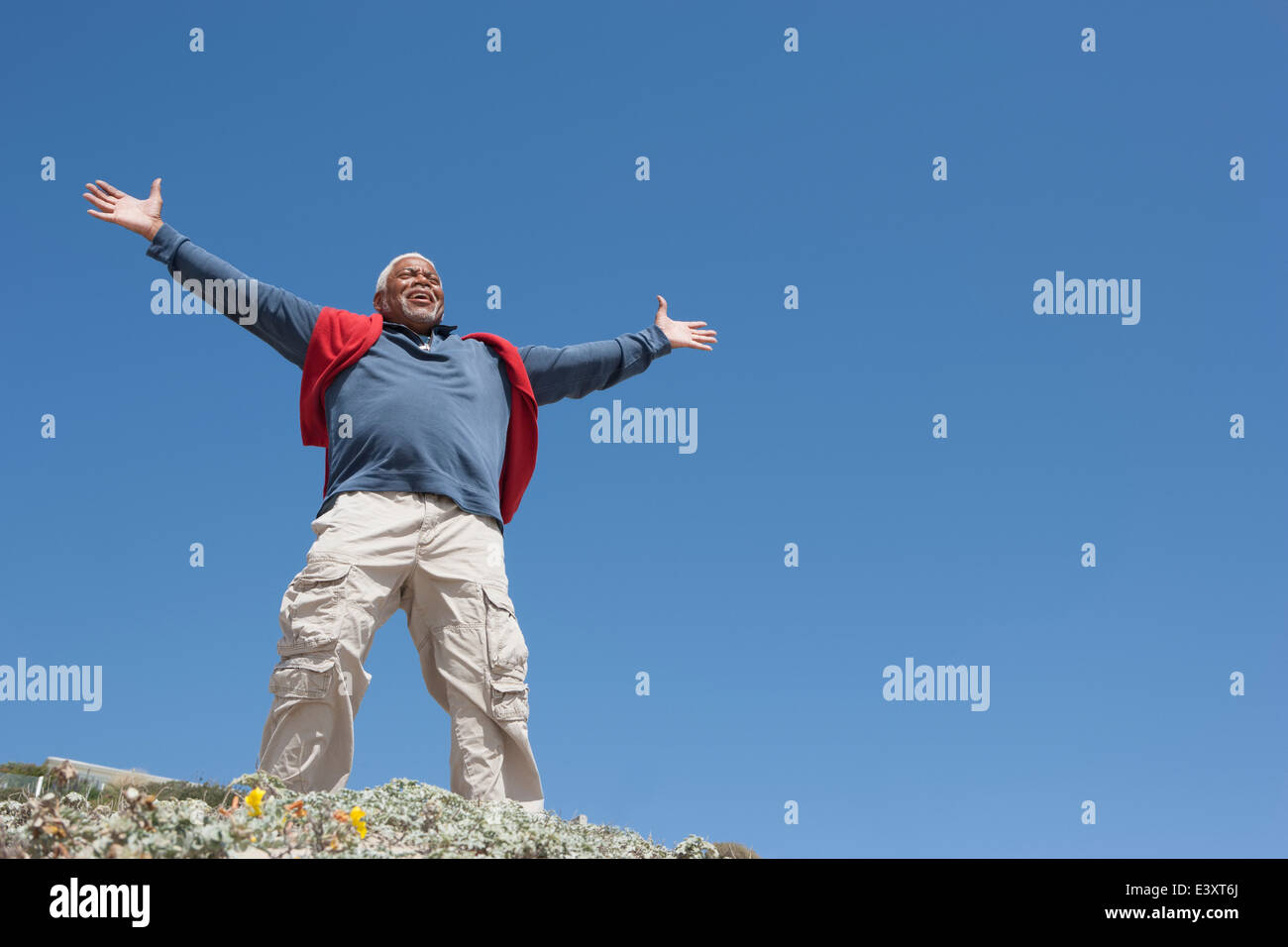 Mixed race Senior man cheering from cliff edge Stock Photo - Alamy