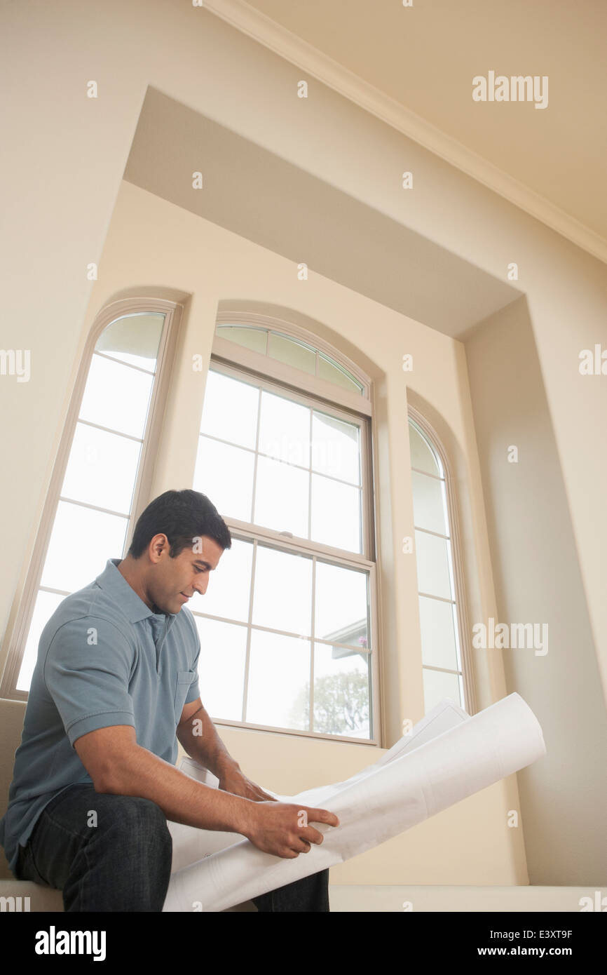 Hispanic man reading blueprints in new home Stock Photo - Alamy