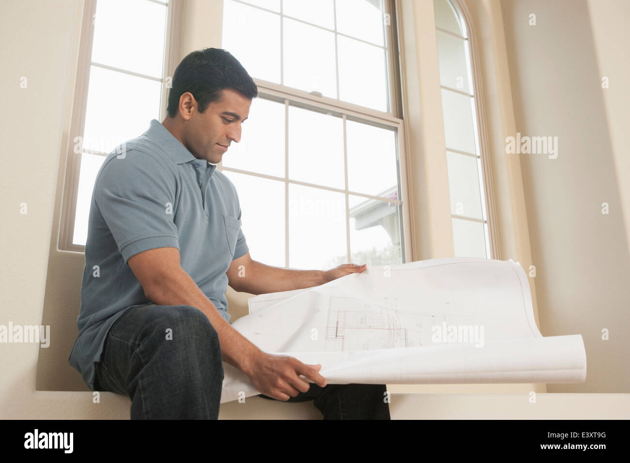 Hispanic man reading blueprints in new home Stock Photo - Alamy