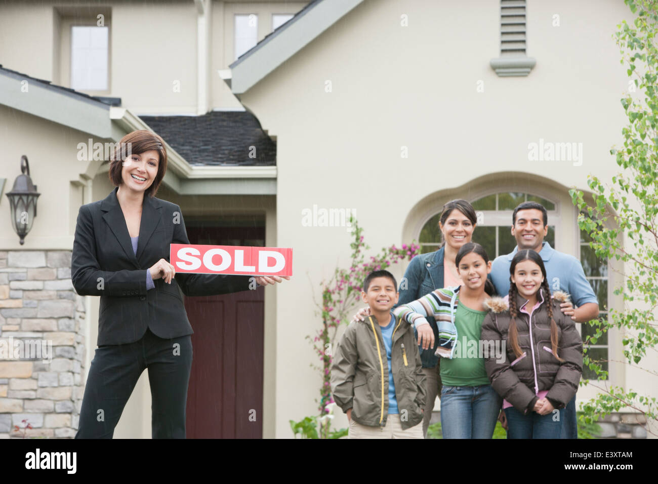 Realtor and family smiling outside new home Stock Photo - Alamy