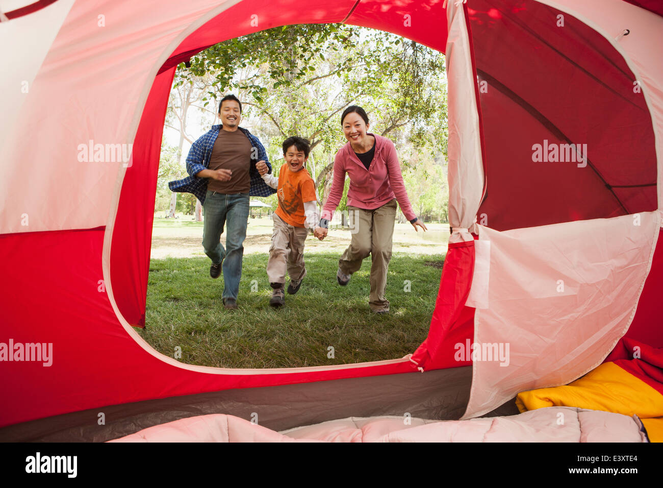 Asian family running to tent at campsite Stock Photo - Alamy