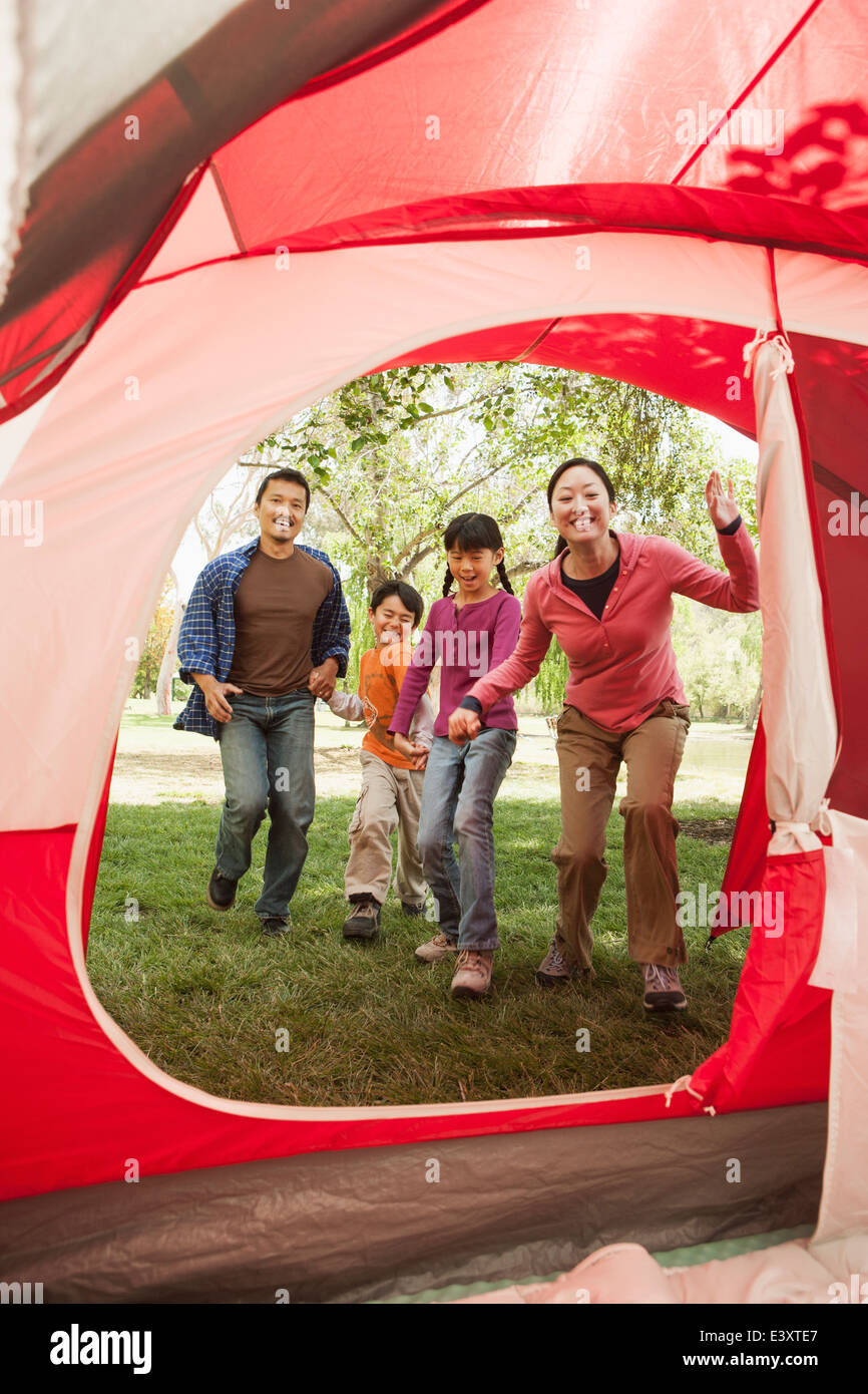 Family running to tent at campsite Stock Photo - Alamy