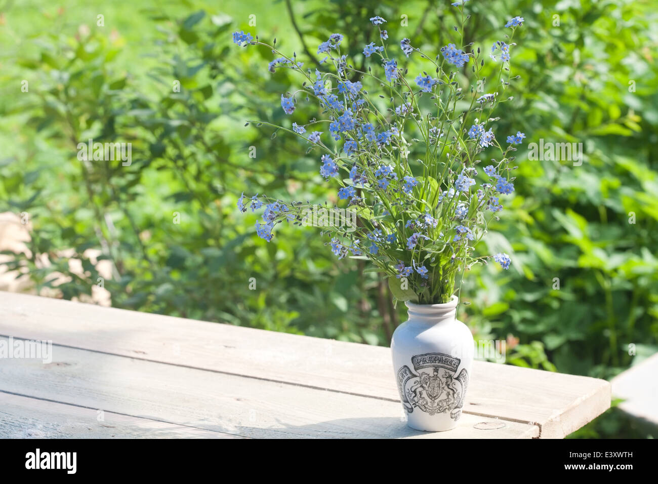 summer bunch of flowers in antique vase on wooden table on outdoor ...