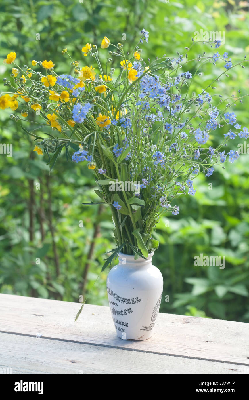 summer bunch of flowers in antique vase on wooden table on outdoor ...