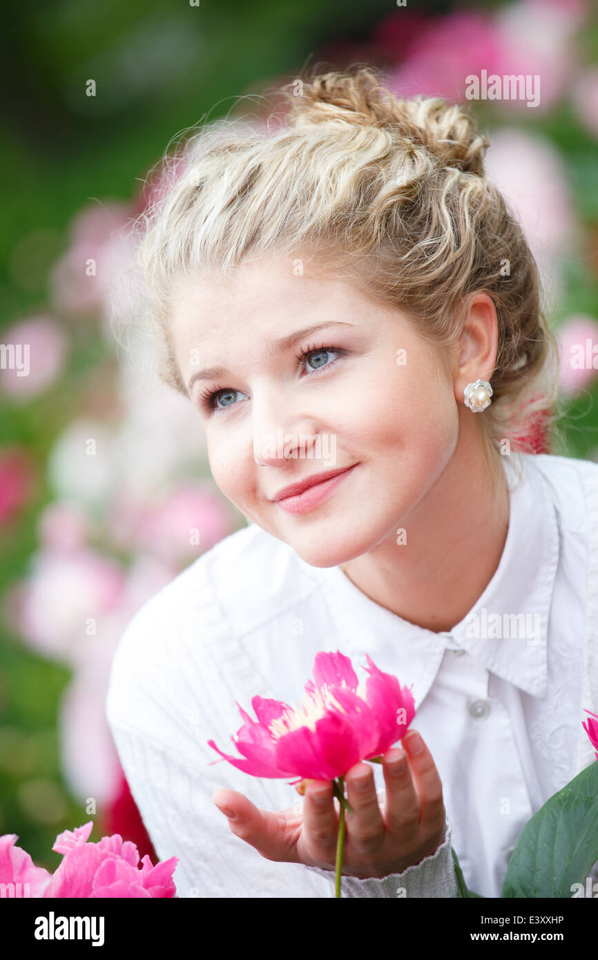 Beautiful happy woman in flower garden smiling Stock Photo - Alamy