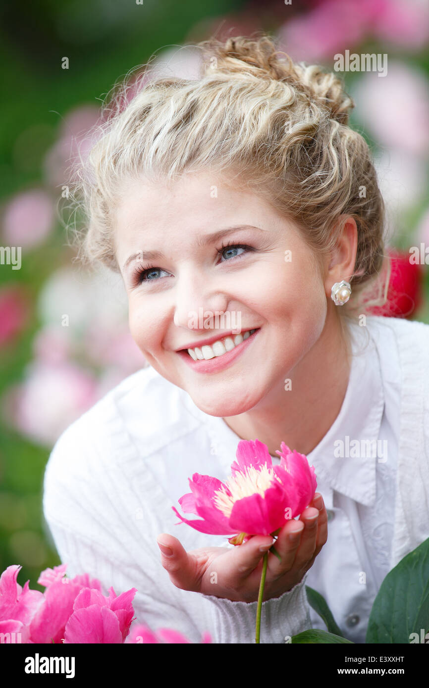 Beautiful happy woman in flower garden smiling Stock Photo - Alamy