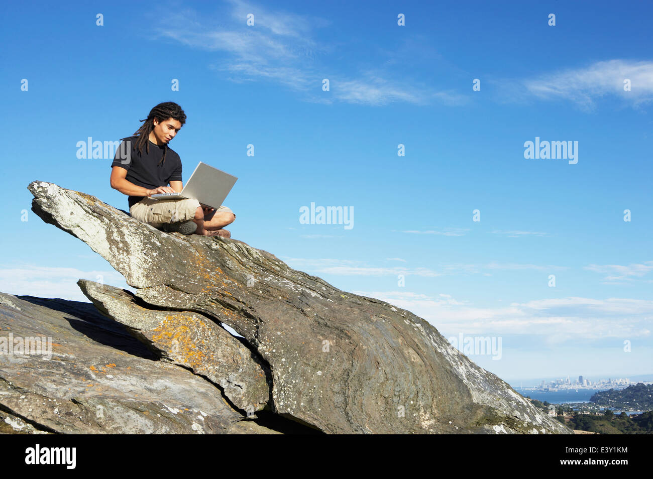Man using laptop on rock Stock Photo - Alamy