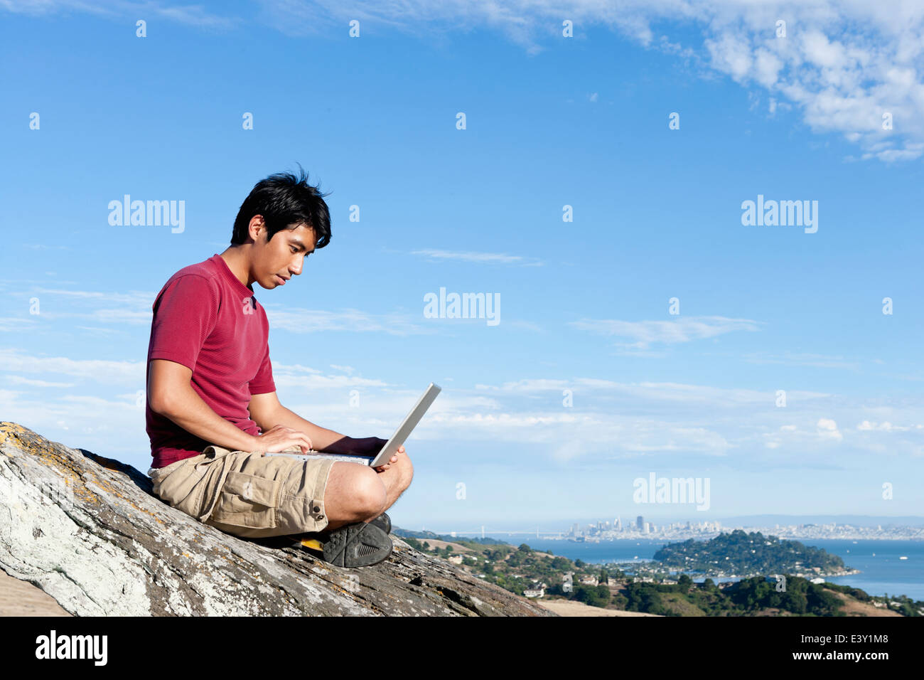 Climber using laptop on rocky hilltop Stock Photo - Alamy