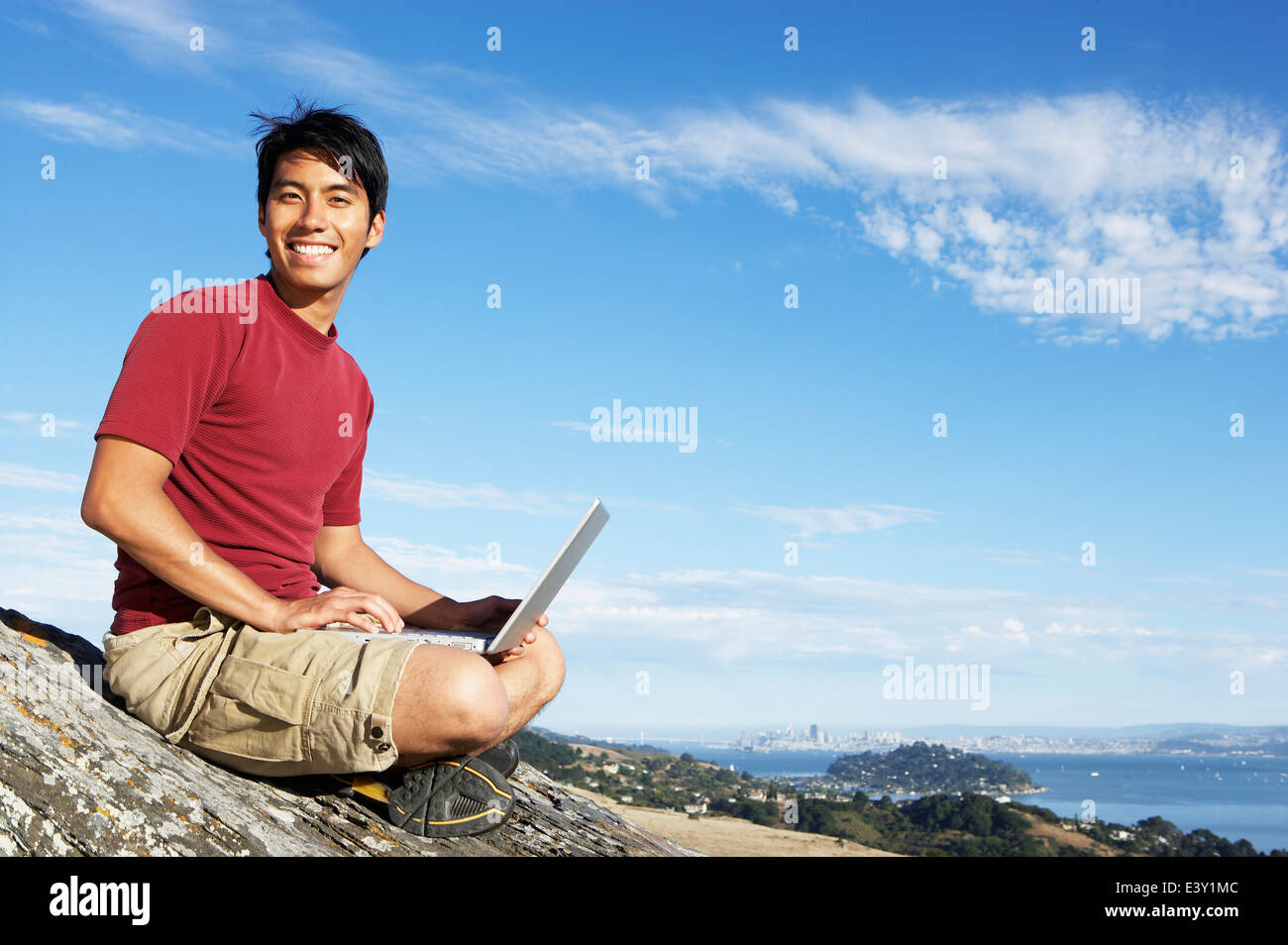Climber using laptop on rocky hilltop Stock Photo - Alamy