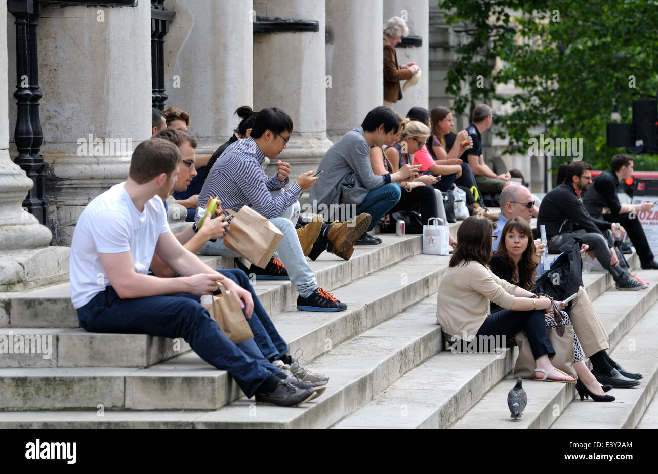 London, England, UK. People sitting on the steps of St Martin in the ...