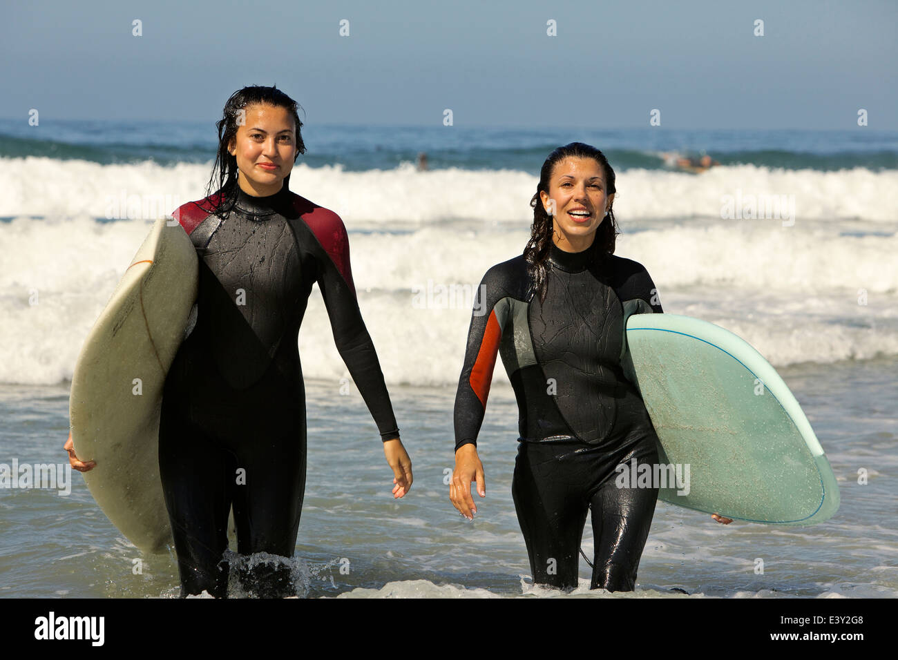 Portrait of smiling surfers walking out of ocean Stock Photo - Alamy