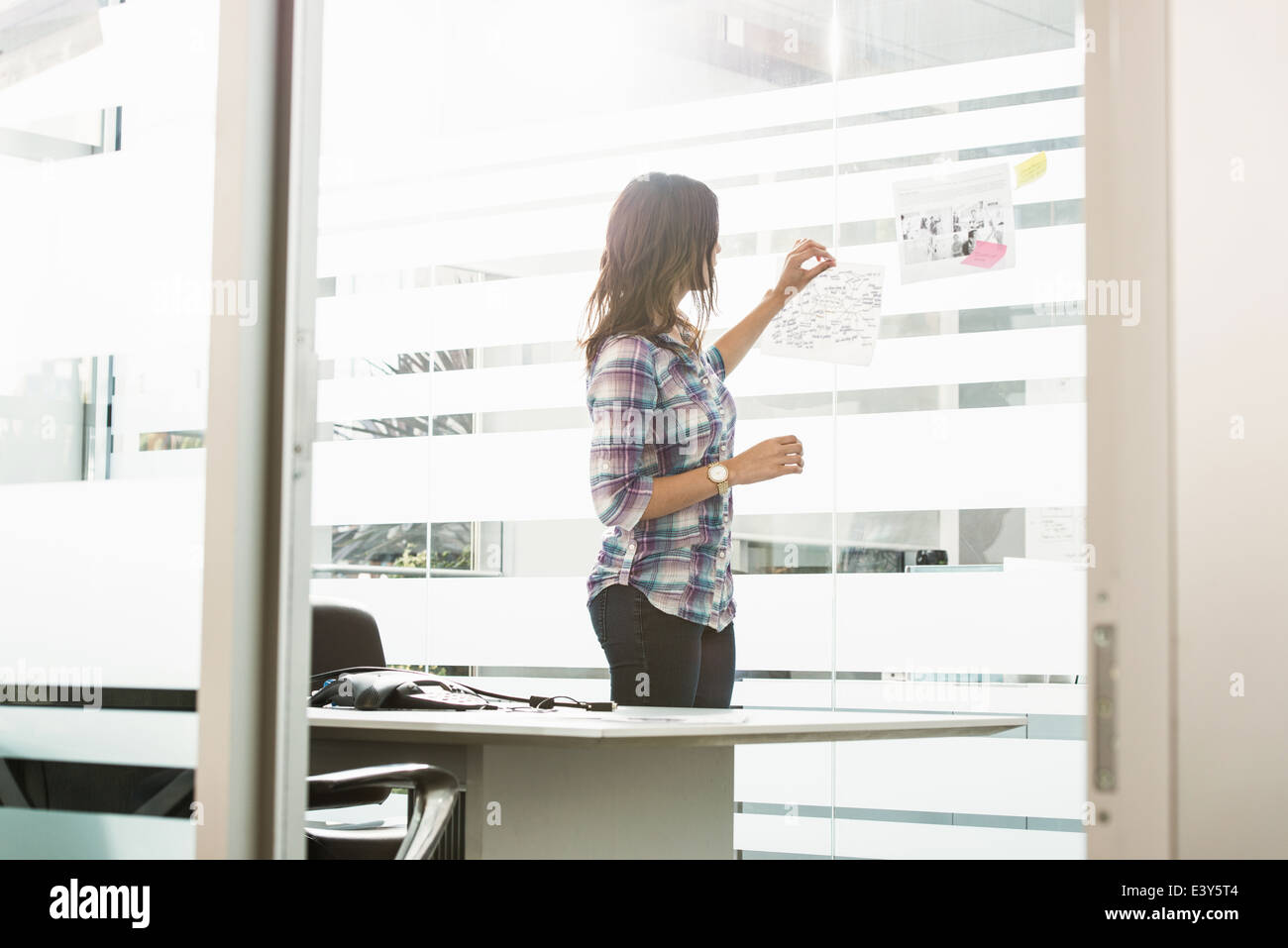 Young businesswoman putting post it notes on office window Stock Photo ...