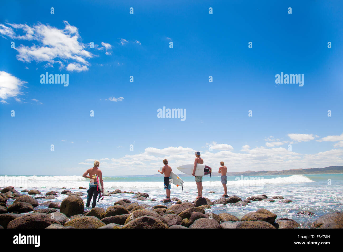 Four young male surfer friends watching sea Stock Photo - Alamy