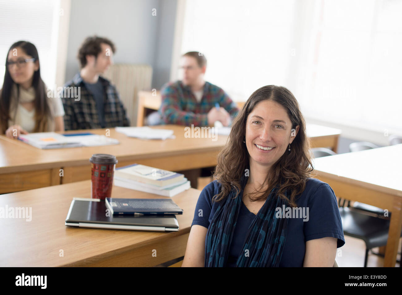 Portrait of a smiling teacher with young college students using ...
