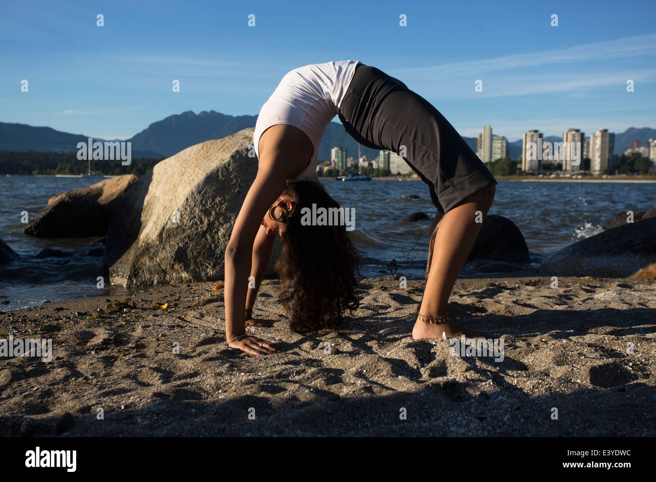 Young Indian woman doing a bridge stretch on the beach in Vancouver ...
