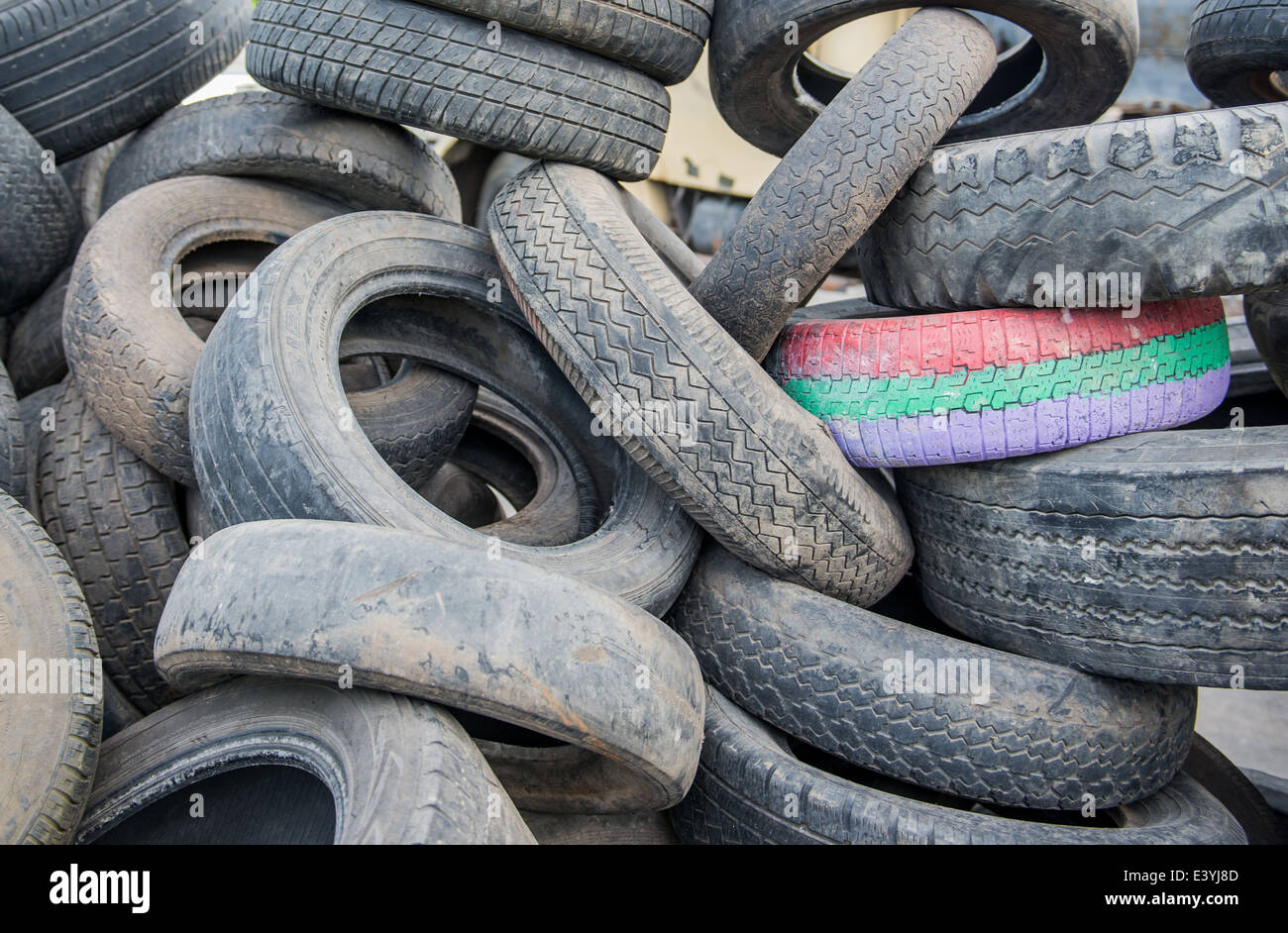 heap of old tires with one colourful tire Stock Photo - Alamy