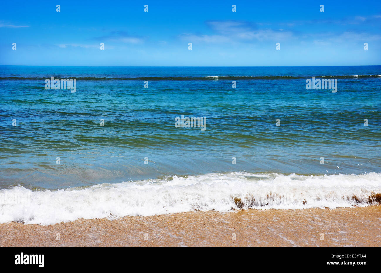 Ocean waves and ripples on sandy beach with blue skies Stock Photo - Alamy