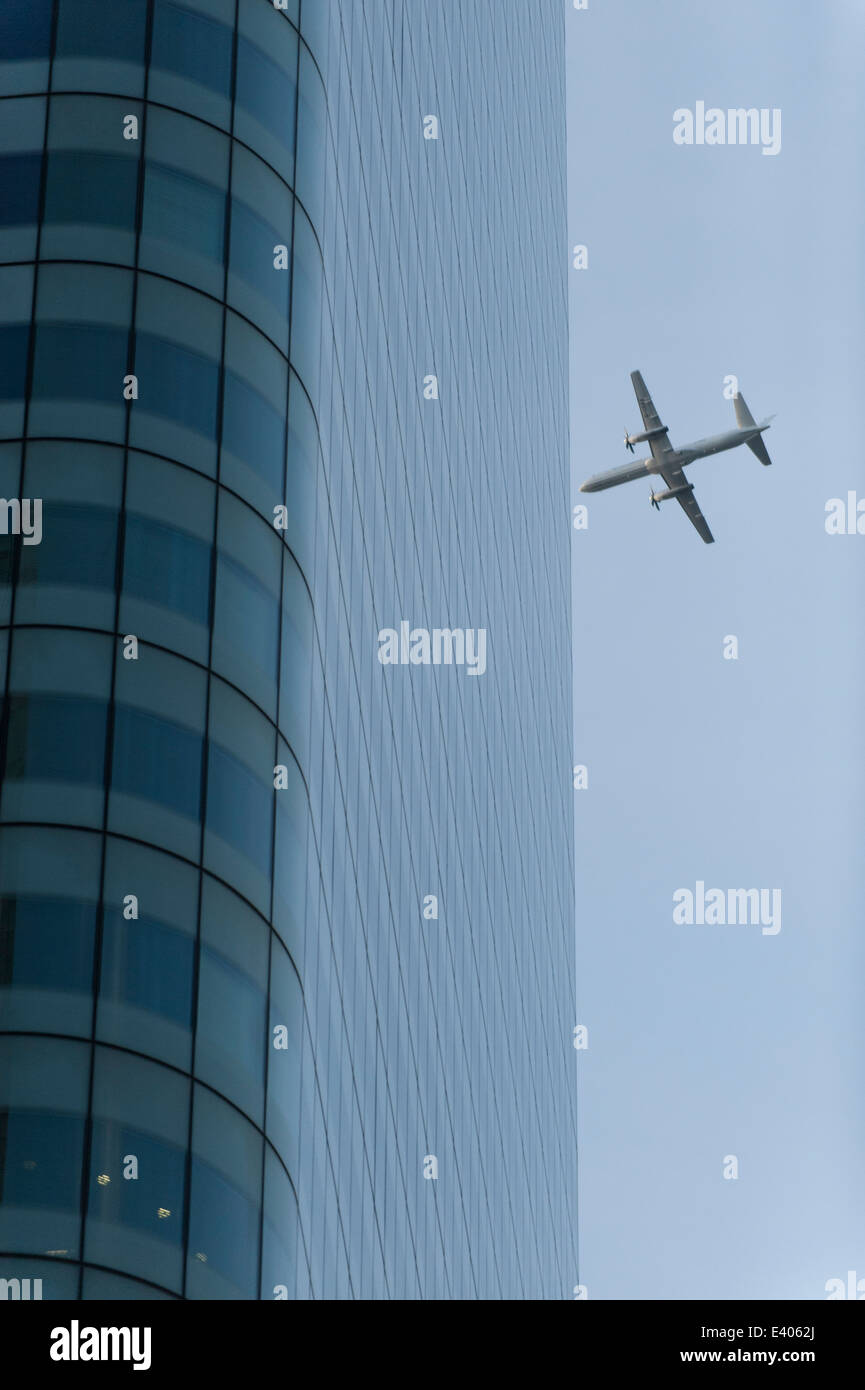 Low flying passenger aircraft flying over skyscraper office building in ...