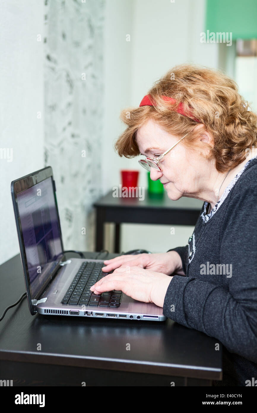 Mature woman typing on a laptop keyboard Stock Photo - Alamy
