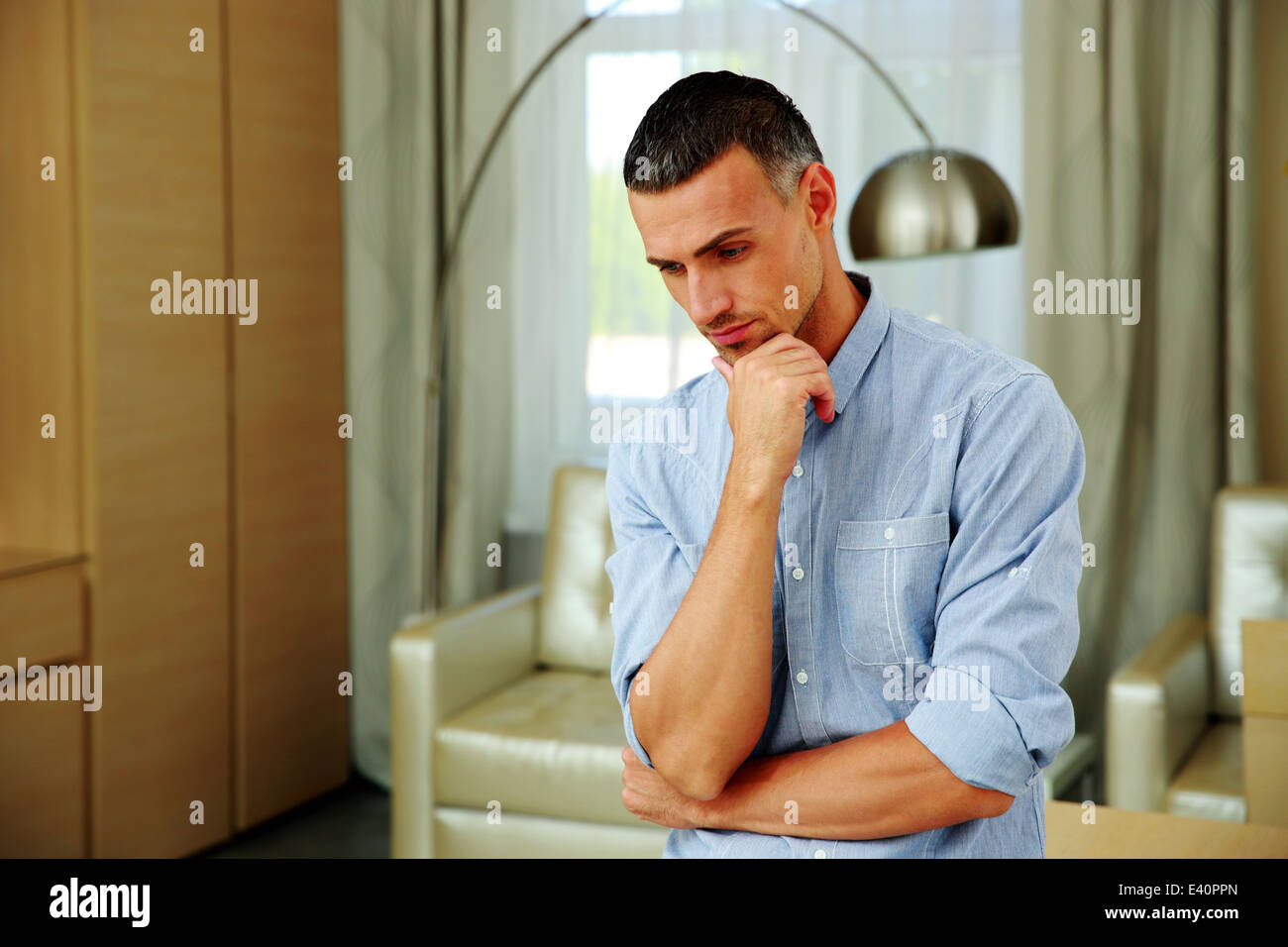 Pensive handsome man standing at home Stock Photo - Alamy