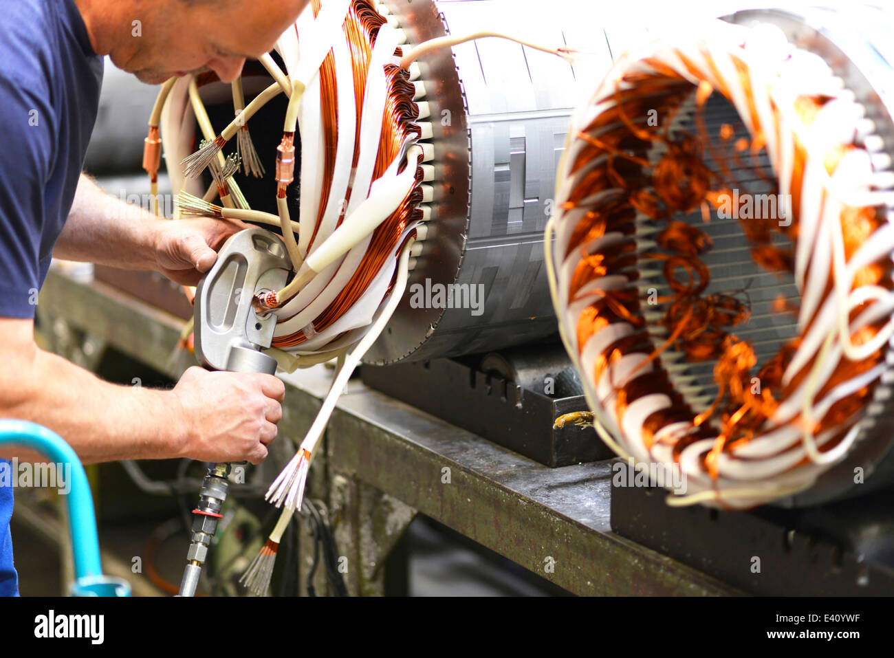 Electric motor production in a factory, worker installing copper wires ...