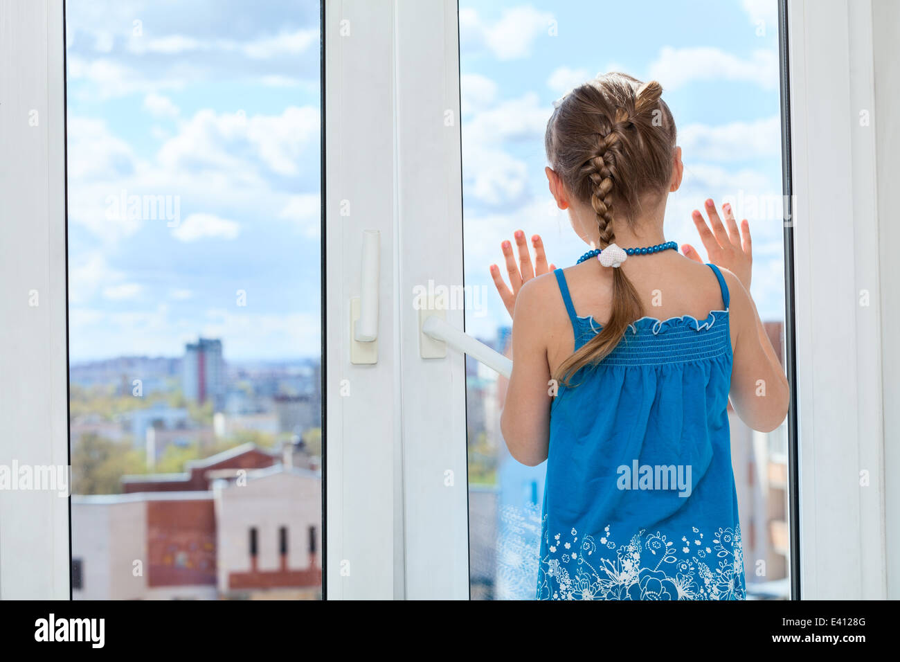 Little child looking through the window glass, copyspace, rear view ...