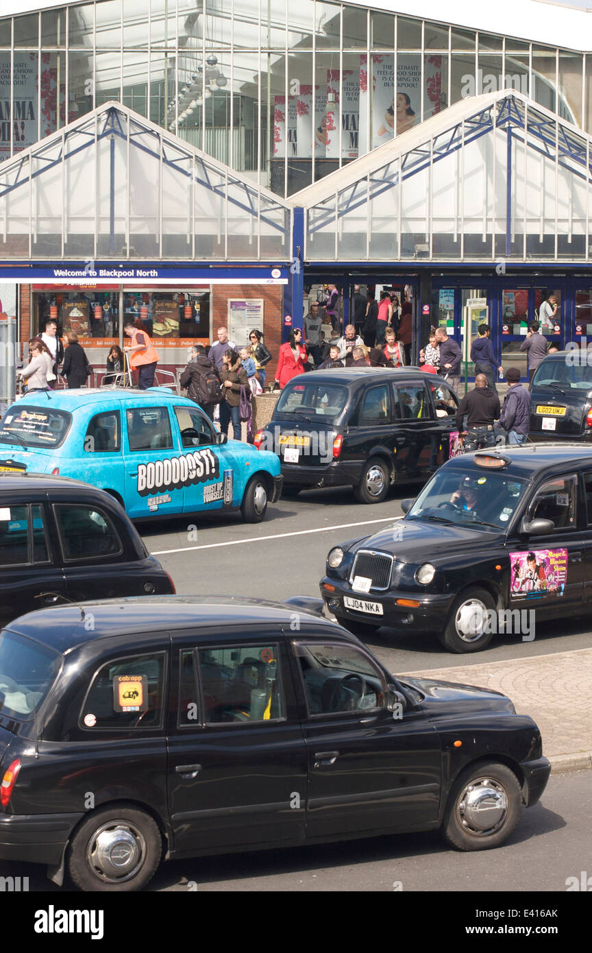 Taxis queue outside a busy Blackpool North railway station in summer ...