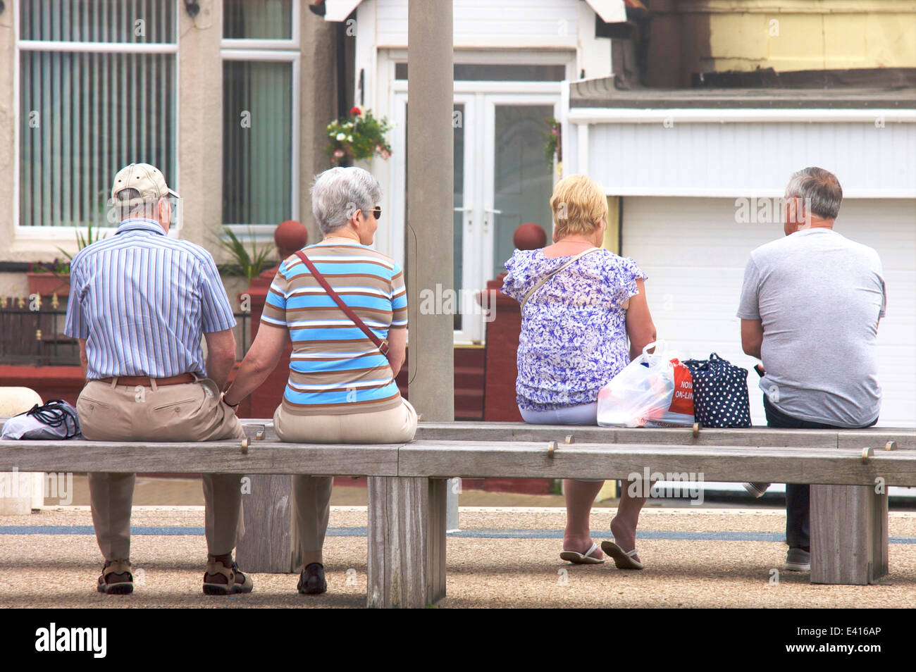 Back view of Four people sat on wooden bench Stock Photo - Alamy