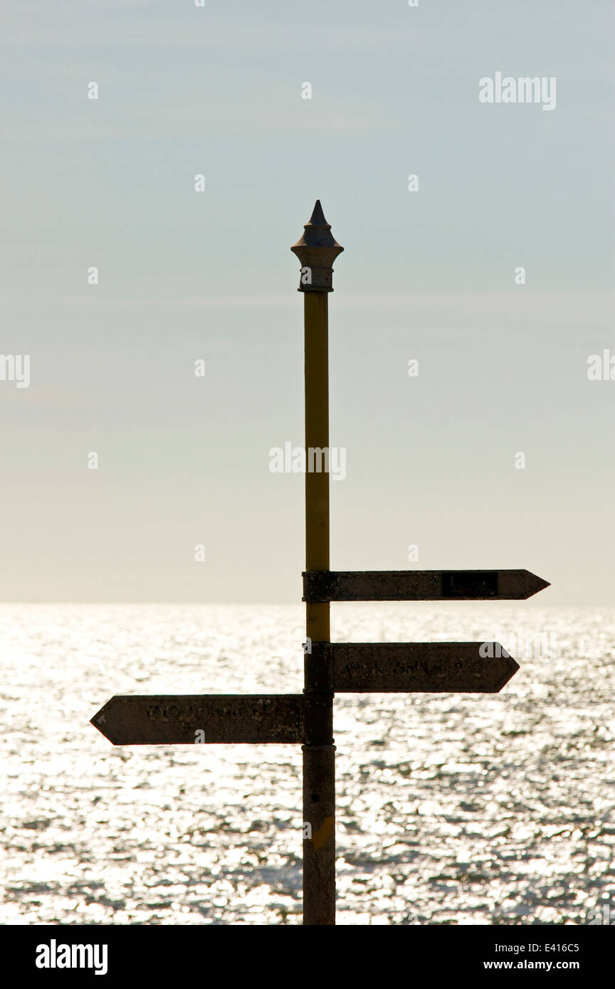 Directions signs silhouetted against bright sea Stock Photo - Alamy