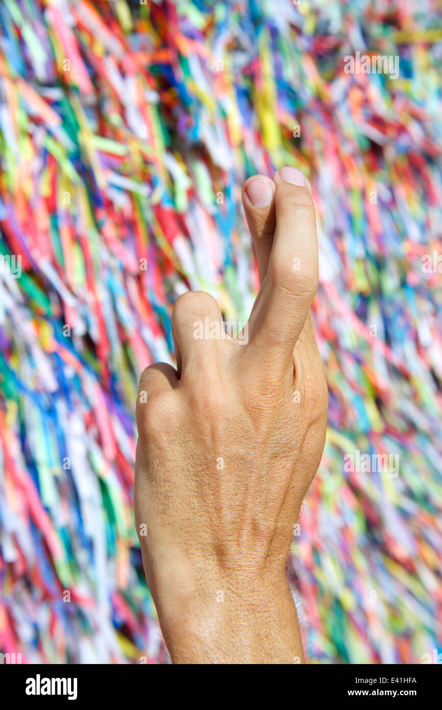 Brazilian hand fingers crossed for luck in front of colorful religious ...
