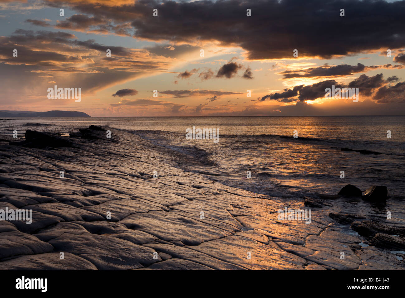 Sun glinting off limestone slab at Kilve beach on the Bristol Channel ...