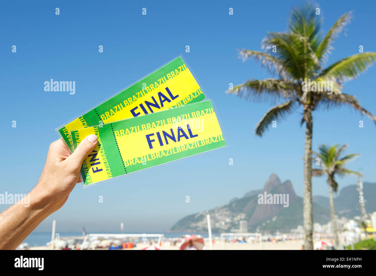 Hand holding pair of Brazil final tickets in front of towering palm ...